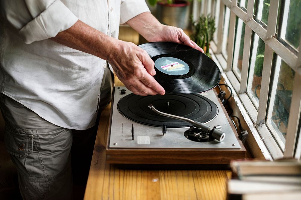 Hands insert vinyl disc to turntable | Photo - rawpixel
