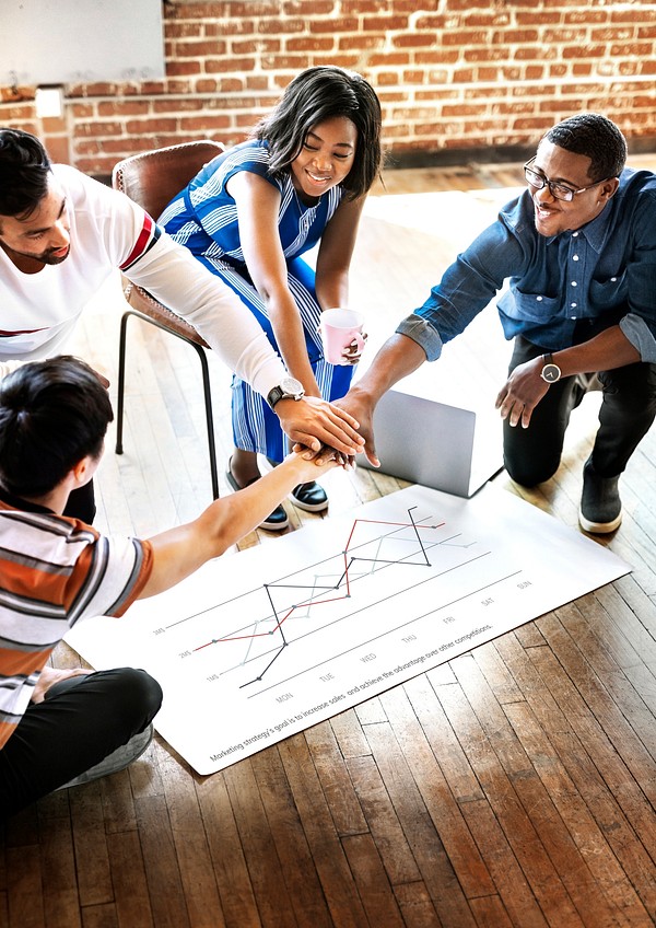 Diverse team stacking hands over a project | Premium PSD Mockup - rawpixel