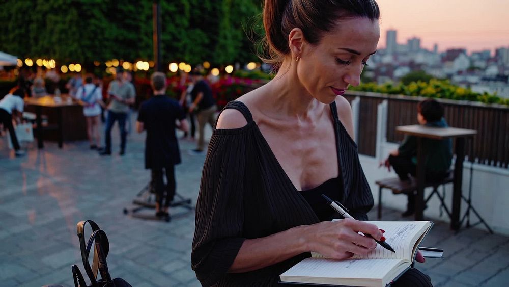 woman writes notebook sunset rooftop, | Free Video - rawpixel