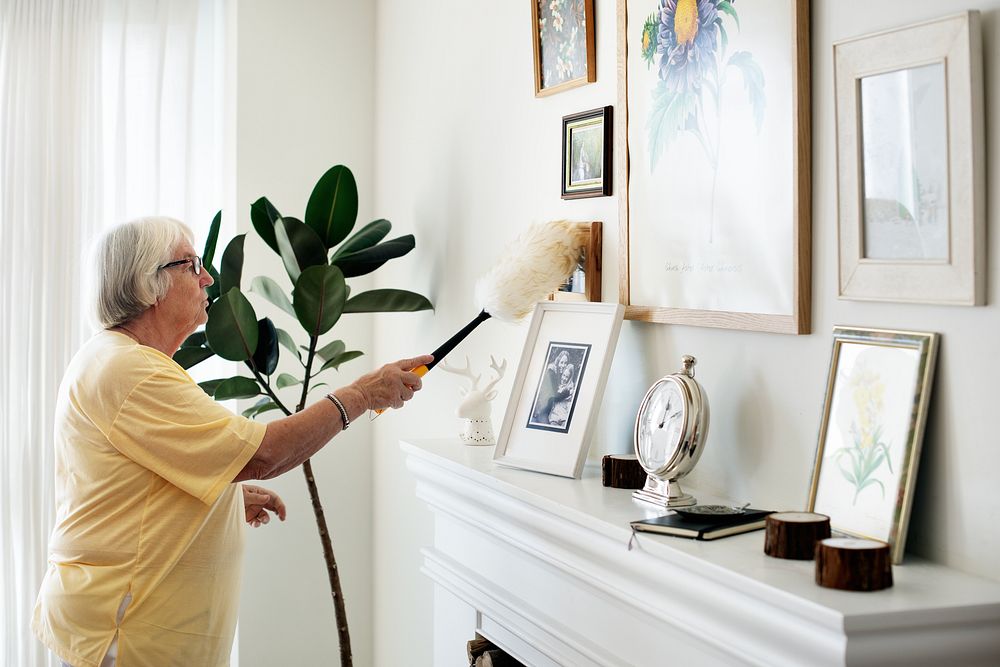 Senior woman dusting picture frames | Free Photo - rawpixel
