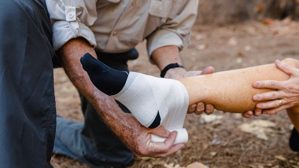 Person bandages another's ankle outdoors | Premium Photo - rawpixel