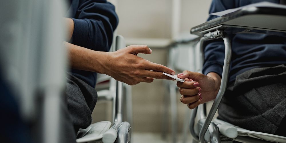 Two people passing note classroom, | Free Photo - rawpixel