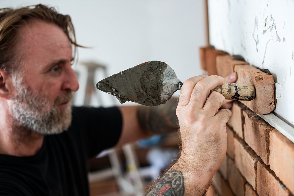 Man laying bricks trowel, focused | Free Photo - rawpixel