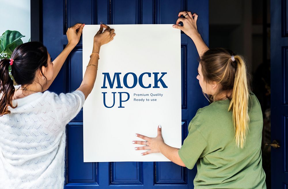 Women putting up a poster | Free PSD Mockup - rawpixel