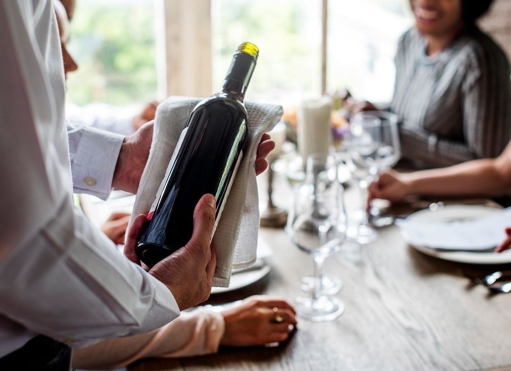 Waiter serving wine to the customers | Photo - rawpixel