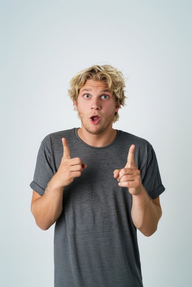 Surprised young man pointing upwards | Free Photo - rawpixel